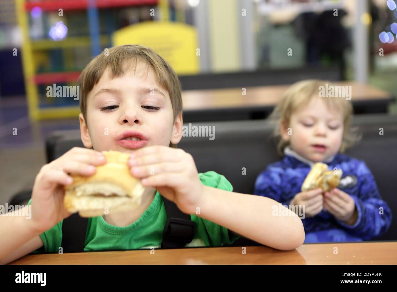 Two children eating sandwiches at table in cafe Stock Photo - Alamy