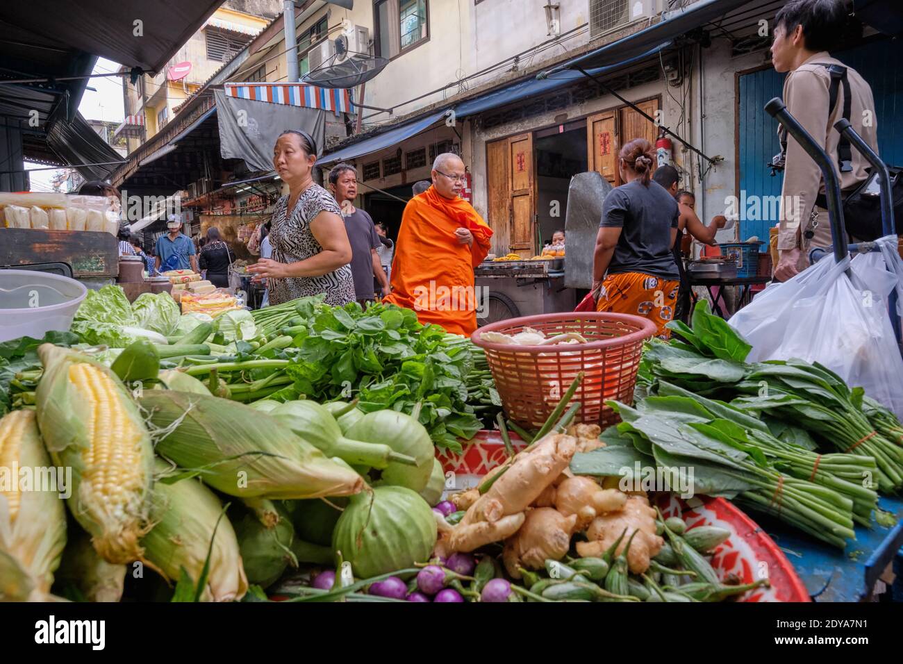 A Thai Buddhist monk passes through a market lane in Bangkok, Thailand ...