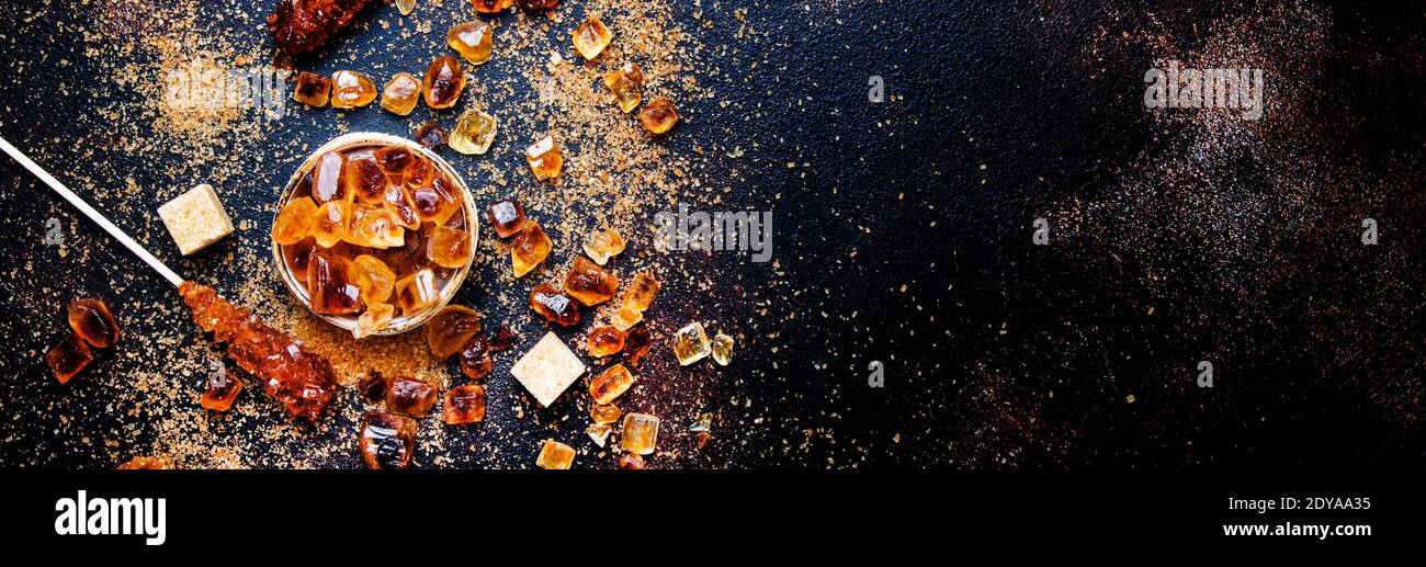 Sweet food background, assorted white and brown sugar on a dark ...