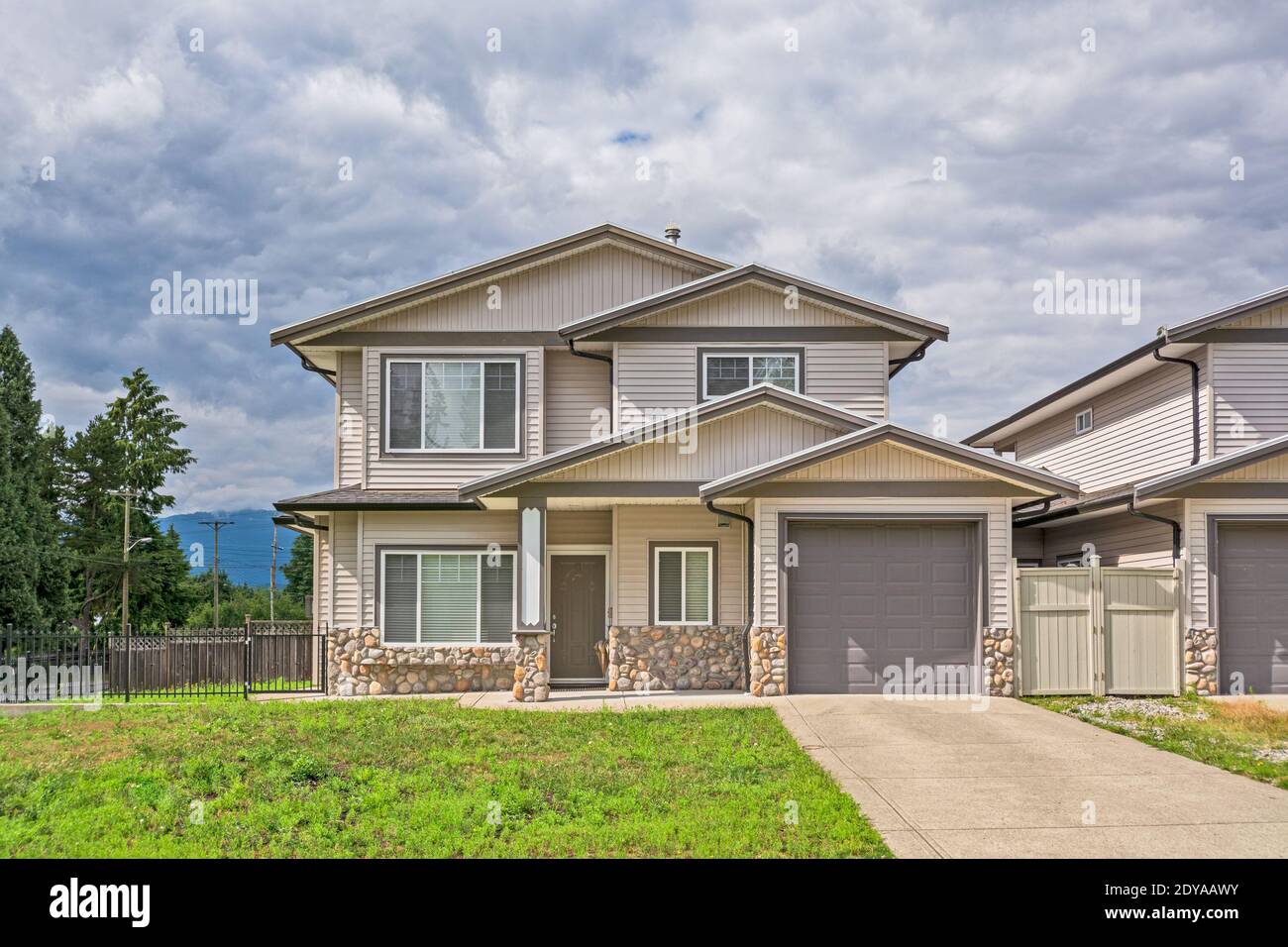 Half of residential duplex building with concrete driveway and lawn in ...