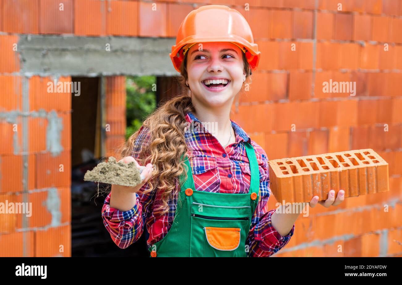 Old brick wall repair. kid wear helmet on construction site. teen girl ...