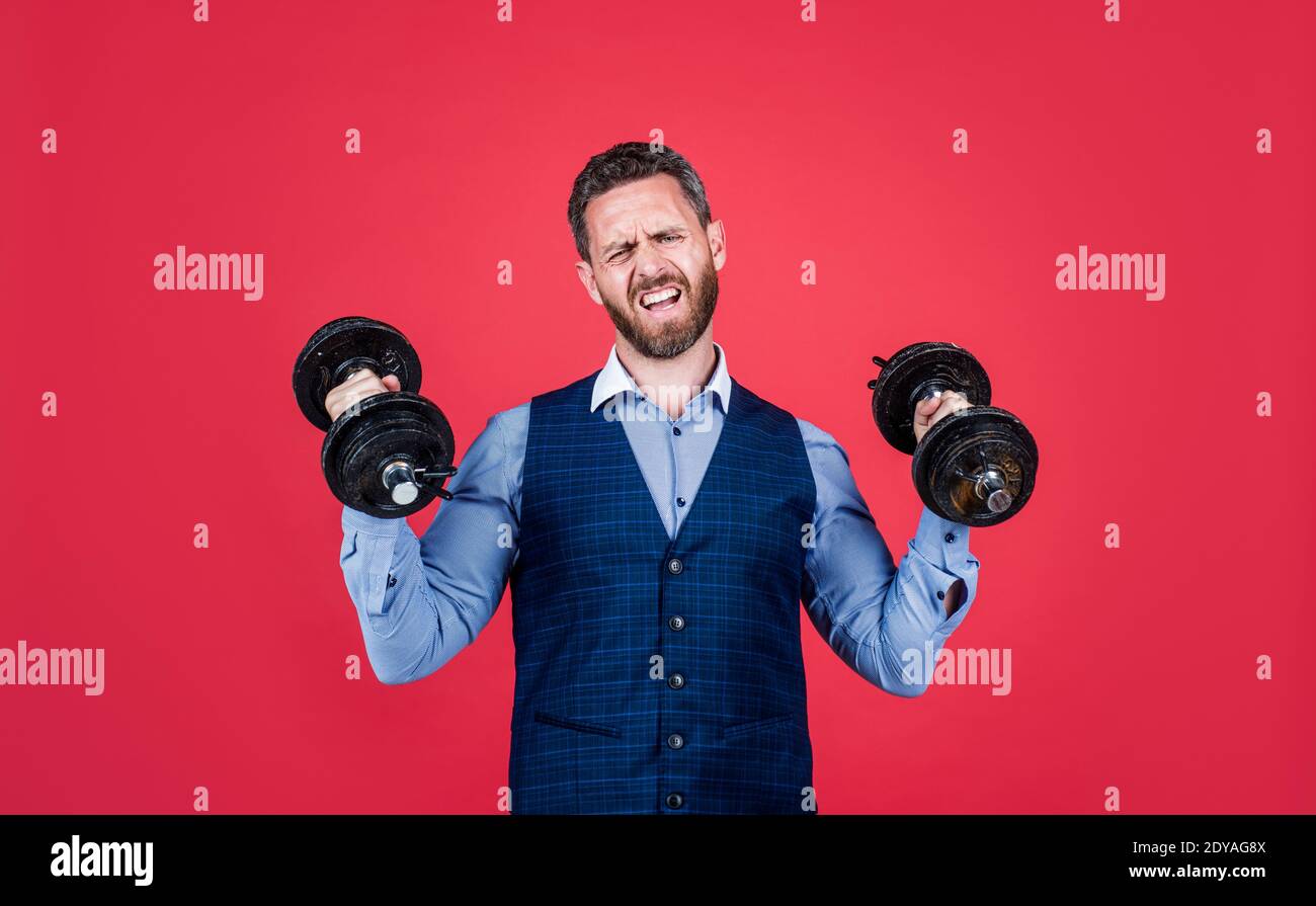 Strong manager in formal style lifting heavy dumbbells red background ...