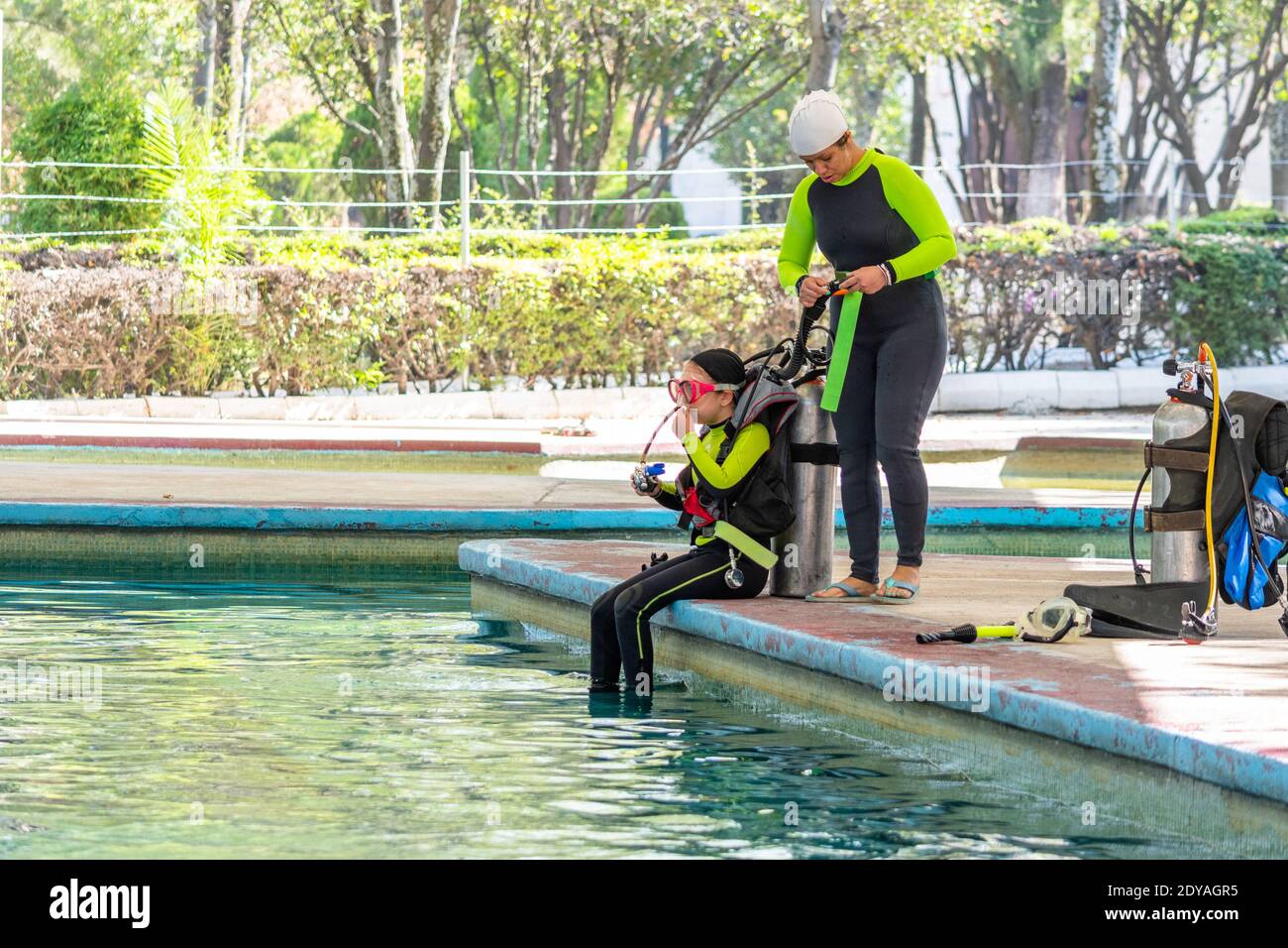 Diving class teacher correctly putting the equipment on her young ...