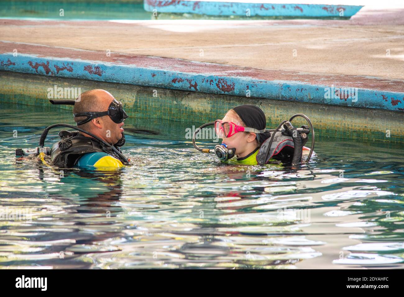 dive master with his young student inside the pool given instructions ...
