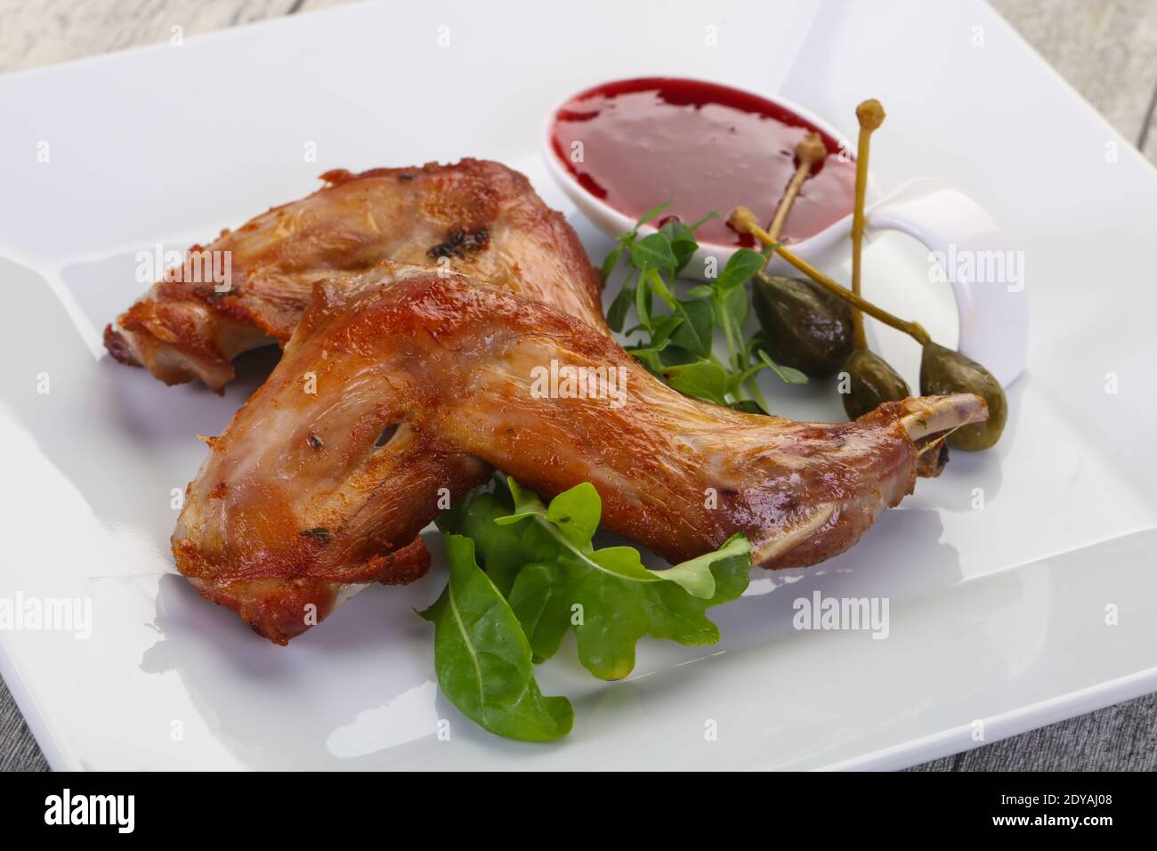 Roasted rabbit legs with cowberry sauce Stock Photo - Alamy