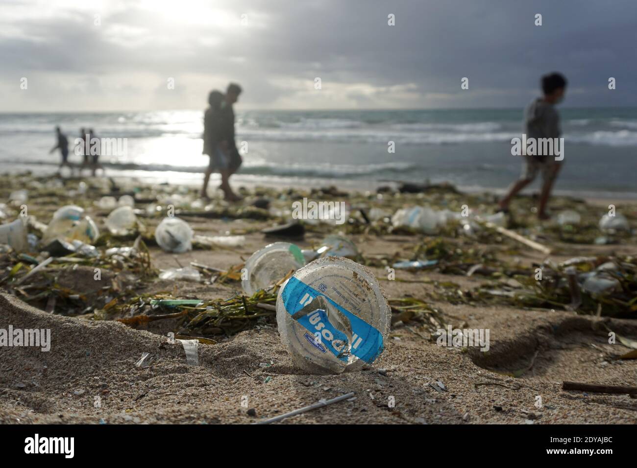 A group of tourist walks along the beach among the trashes.Tons of ...