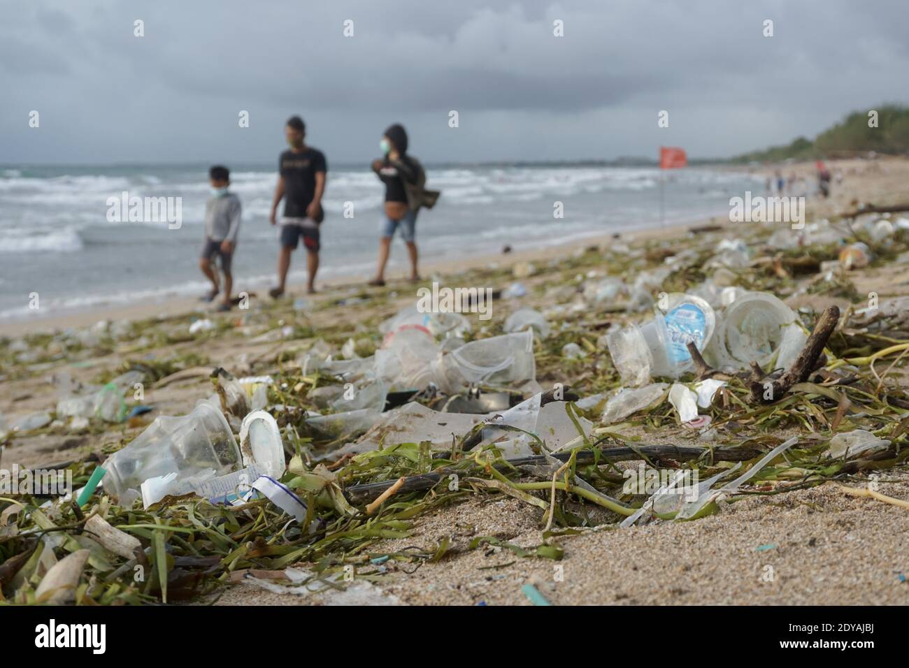 A group of tourist walks along the beach among the trashes.Tons of ...