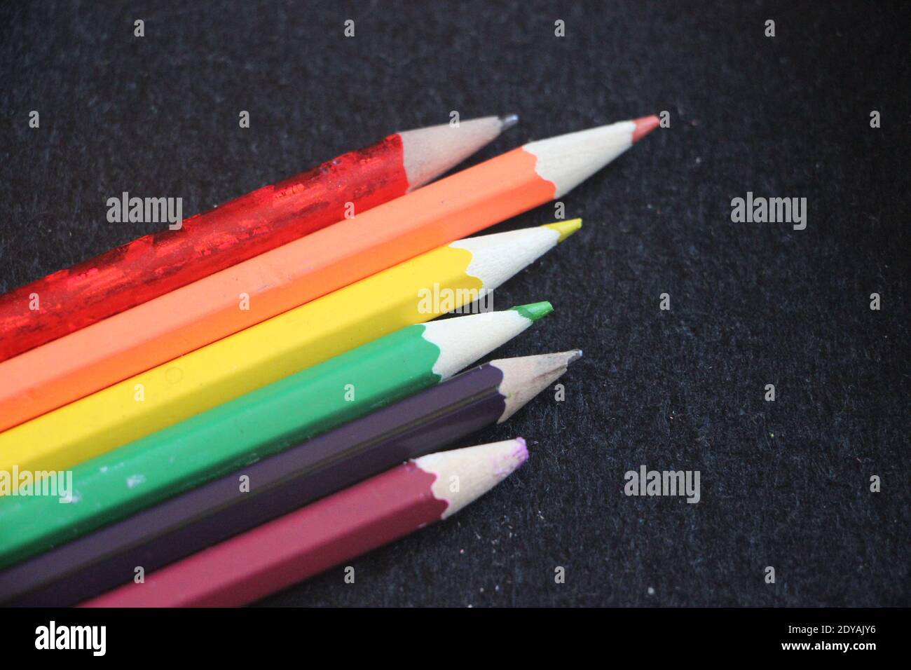 Colored pencils on dark grey background. Creativity concept. Equality ...