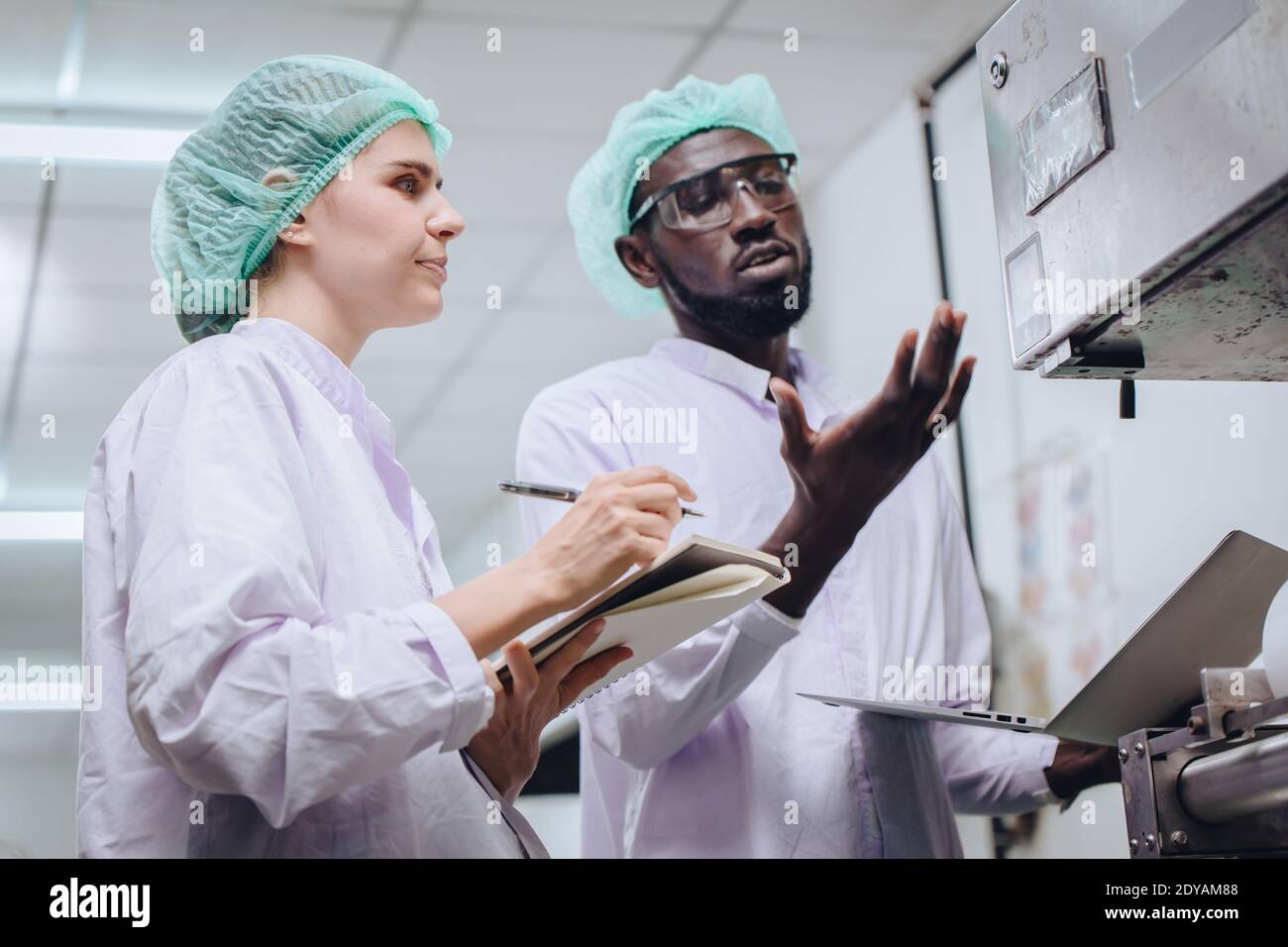 Woman production supervisor working with African worker in food factory ...