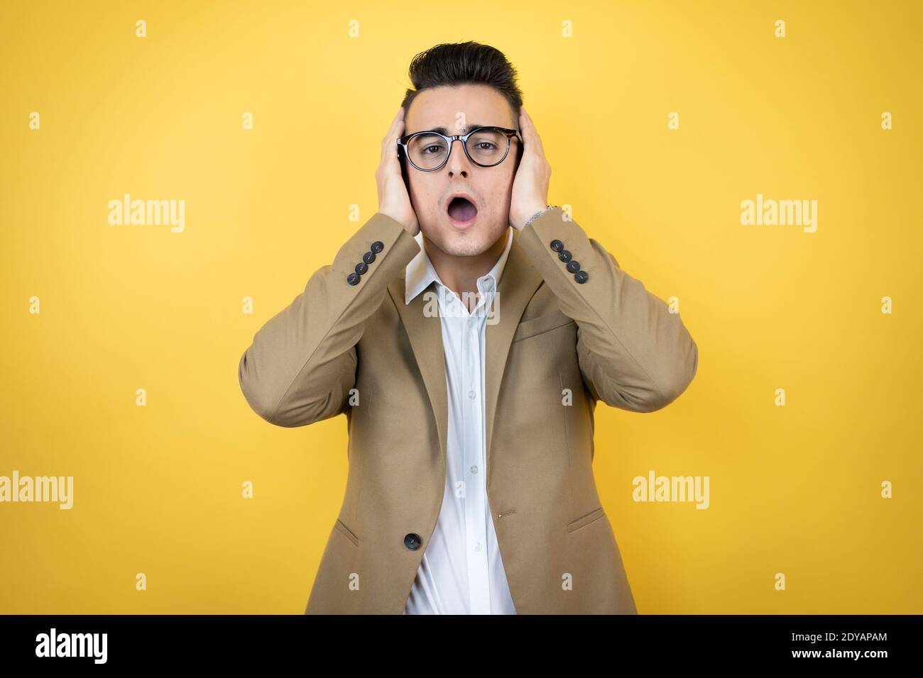 Young business man over isolated yellow background crazy and scared ...