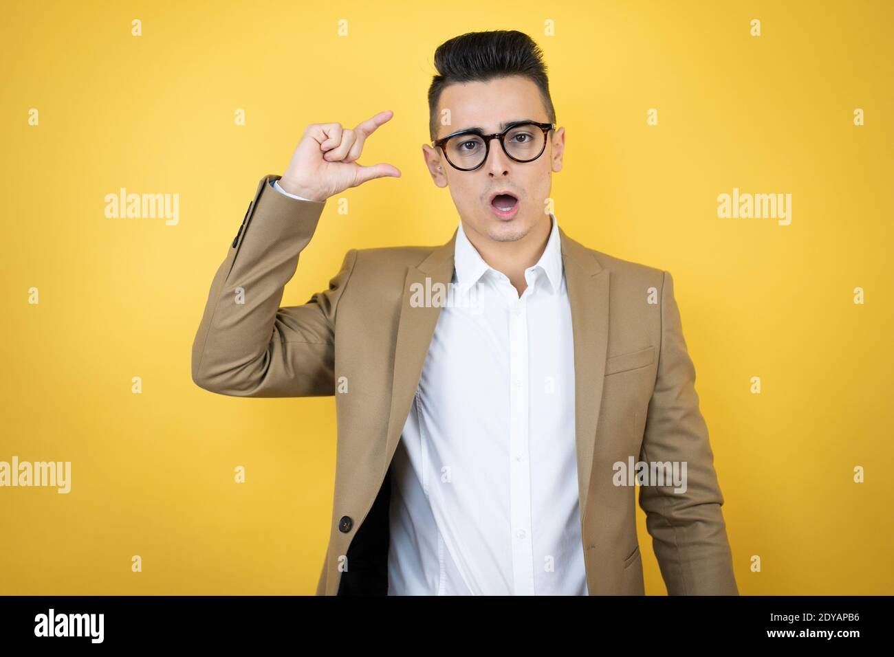 Young business man over isolated yellow background smiling and ...