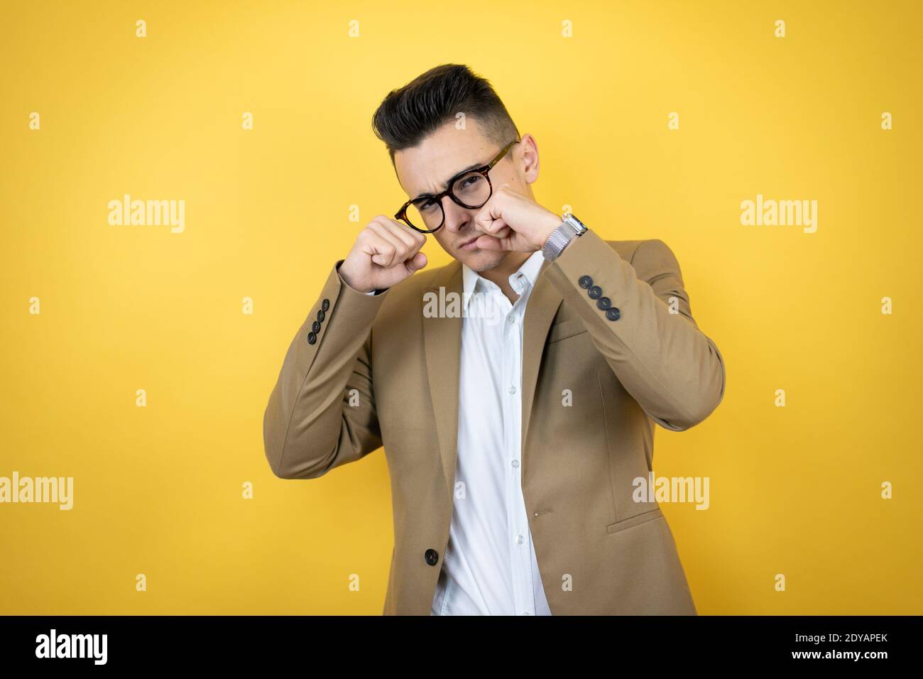 Young business man over isolated yellow background depressed and worry ...
