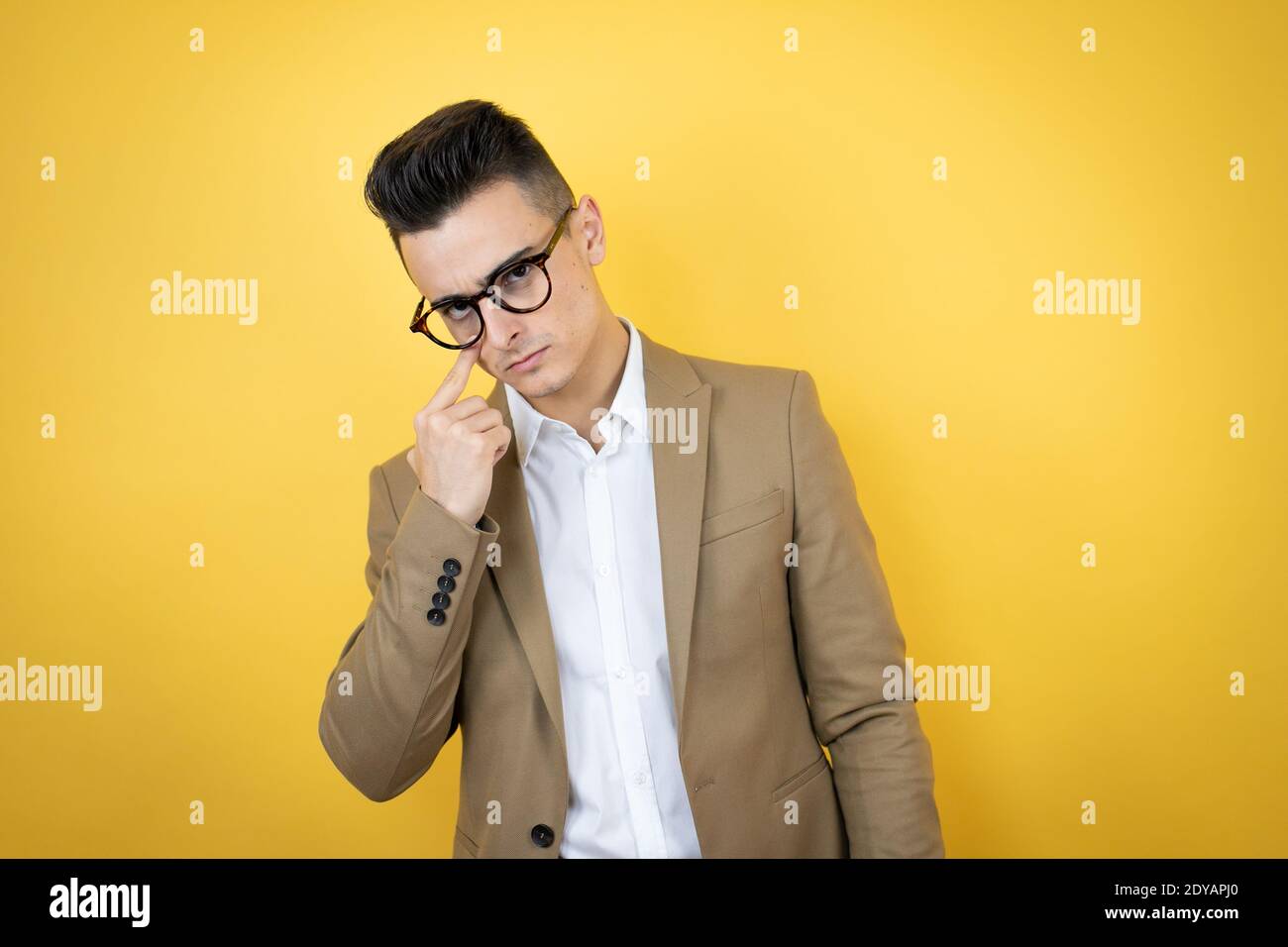 Young business man over isolated yellow background Pointing to the eye ...