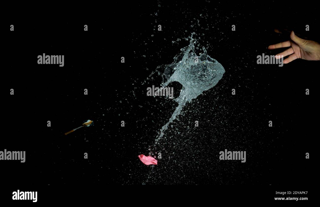 A high-speed image of a thrown dart hitting a Water Balloon, and ...