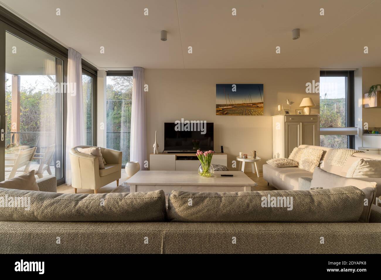 Modern living room with dune facing terrace view in the evening sun ...
