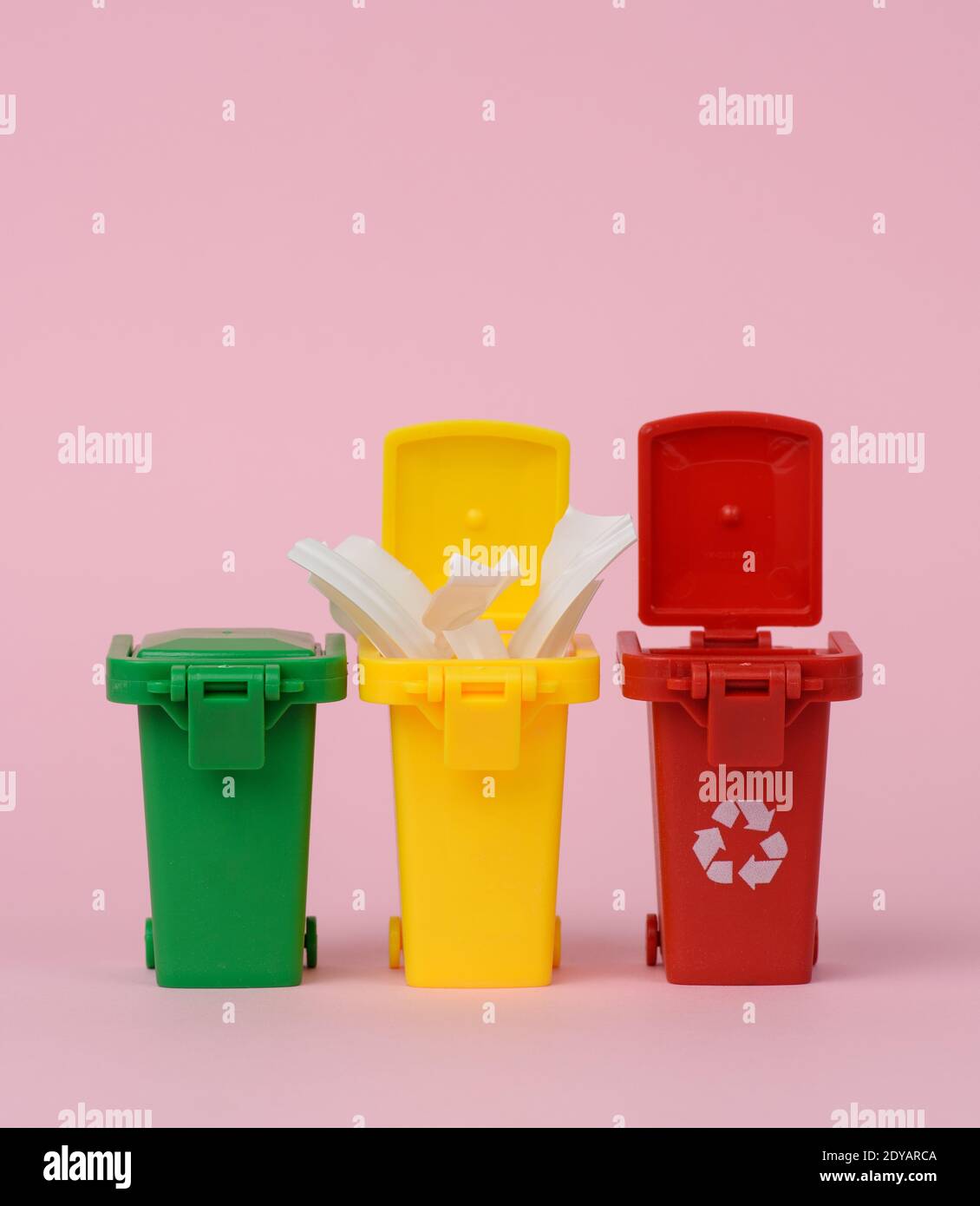 three multi-colored plastic containers on a pink background, the ...