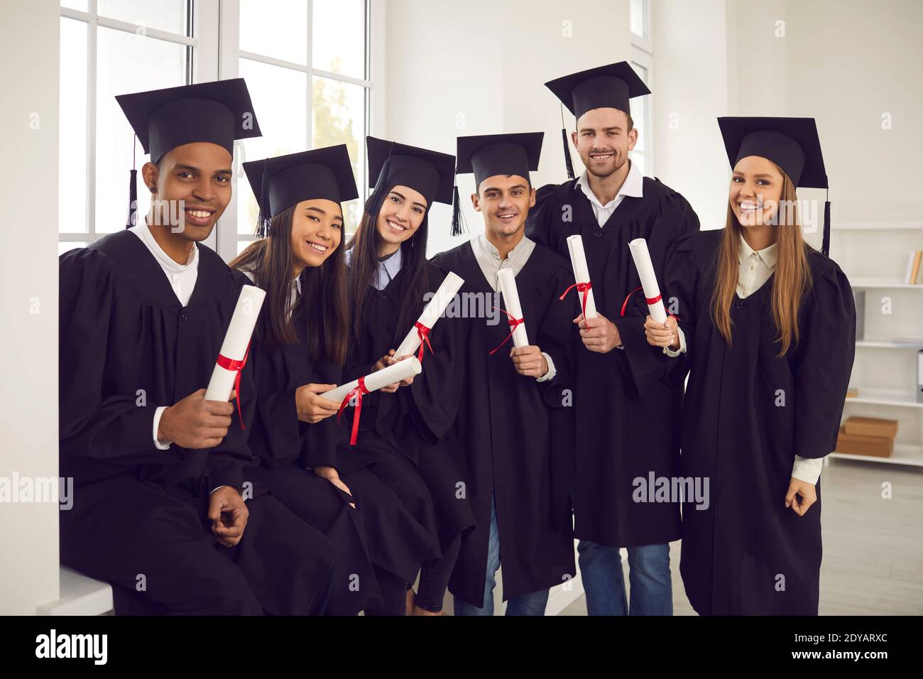 Group of happy international university graduates holding diplomas and ...
