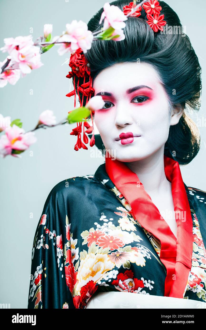 young pretty geisha in black kimono among sakura, asian ethno close up ...