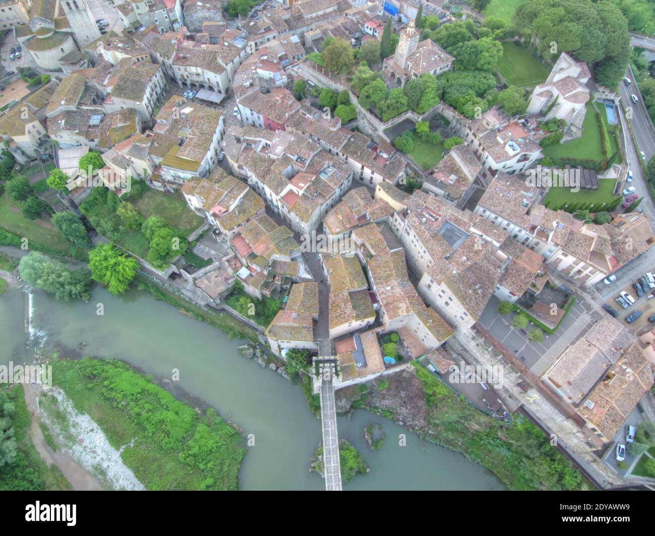 A top view of a city between the forest alongside a river with multiple ...