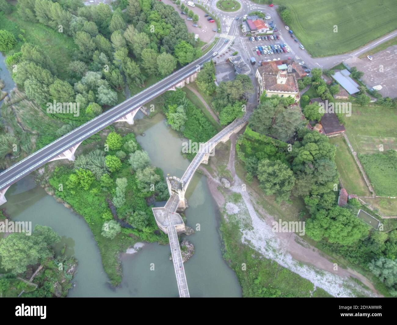 A top view of a city between the forest alongside a river with multiple ...