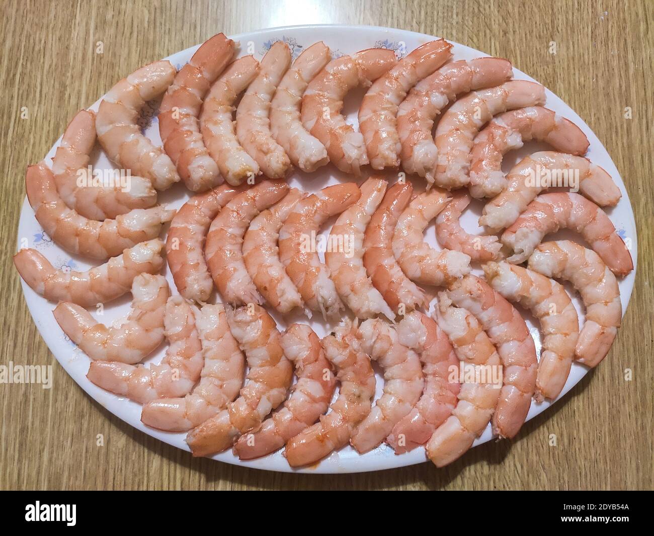 Cooked and peeled whole prawns placed together on a white plate ...