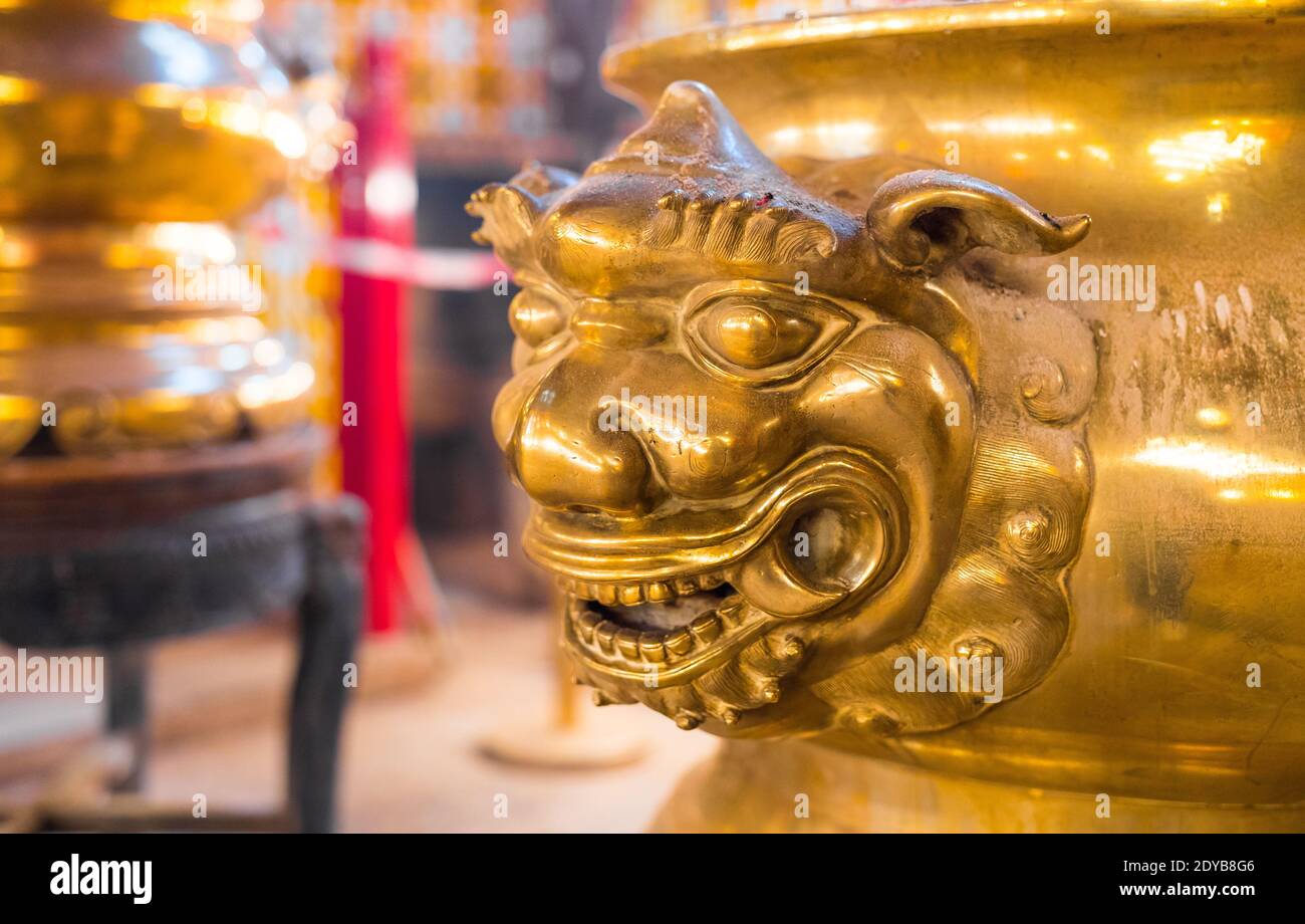 Lion face embbeded onto an incense golden cauldron. Man Mo Temple ...