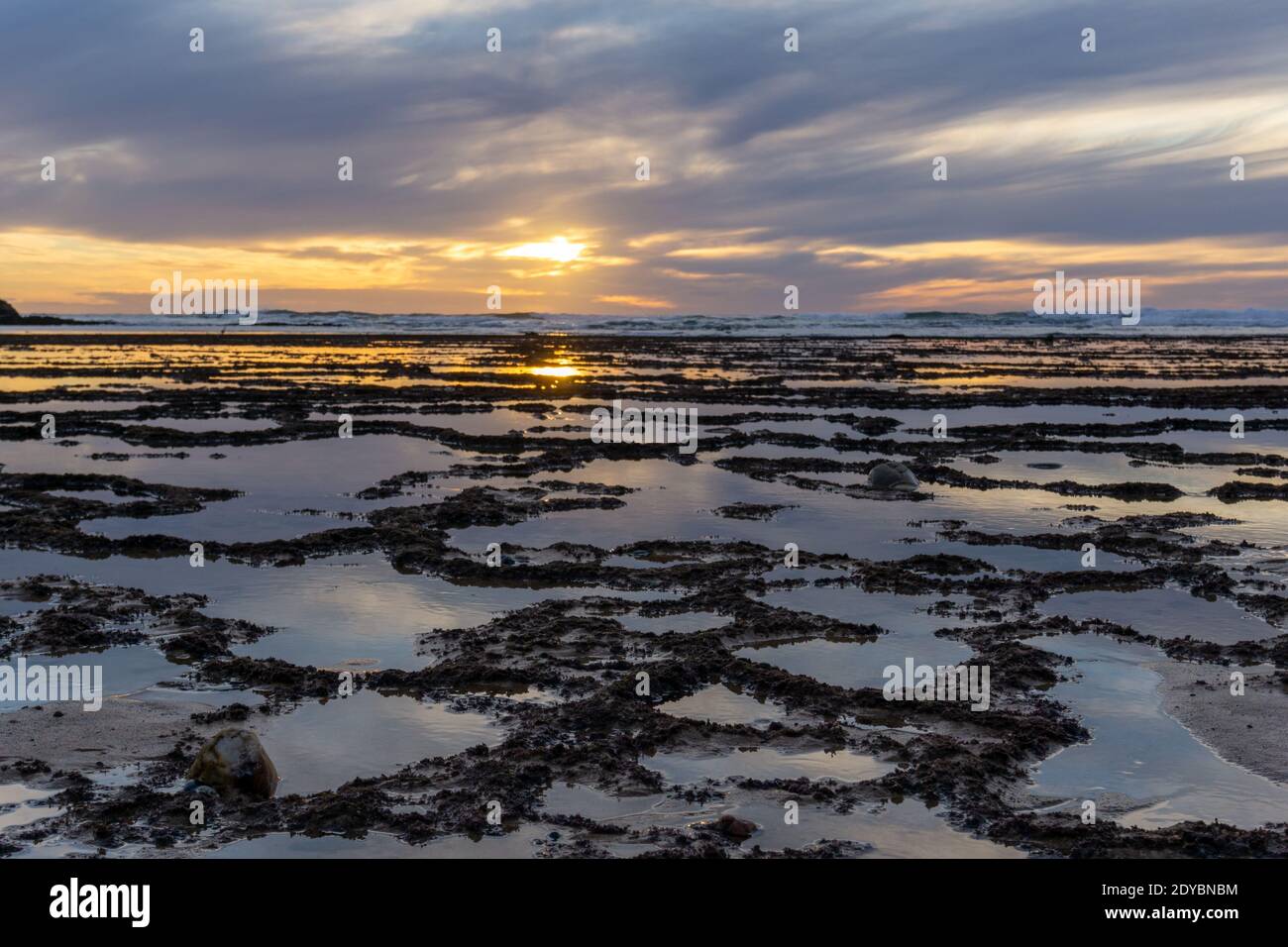 A beautiful sunset over the ocean with rocky beach and tidal pools in ...