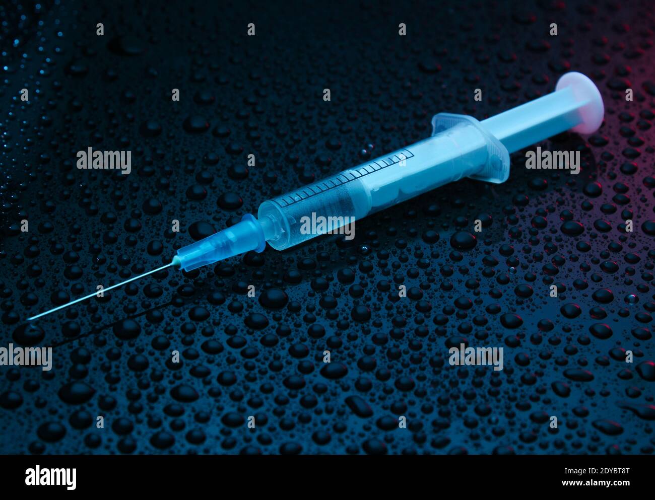 Drug concept, addiction. Syringe on a dark background with water drops ...