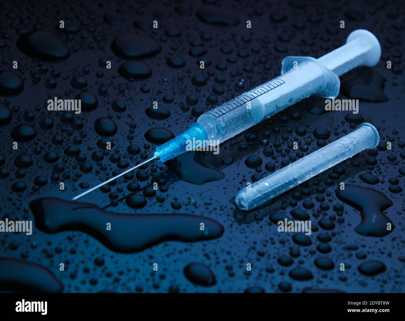 Drug concept, addiction. Syringe on a dark background with water drops ...