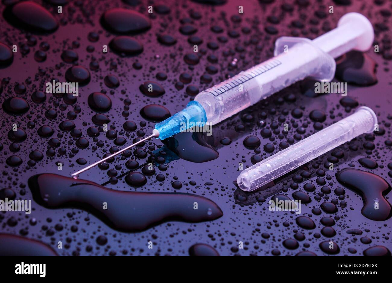 Drug concept, addiction. Syringe on a dark background with water drops ...