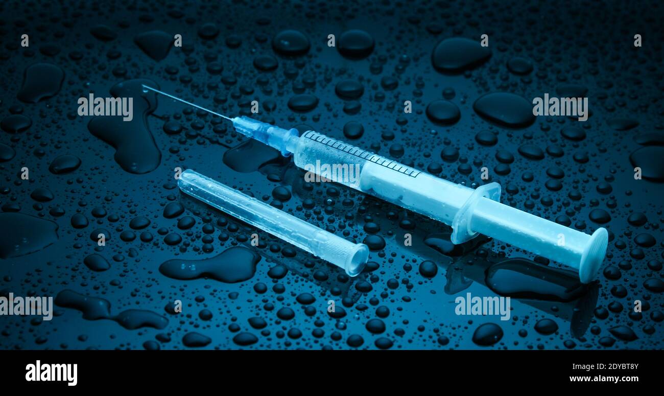 Drug concept, addiction. Syringe on a dark background with water drops ...