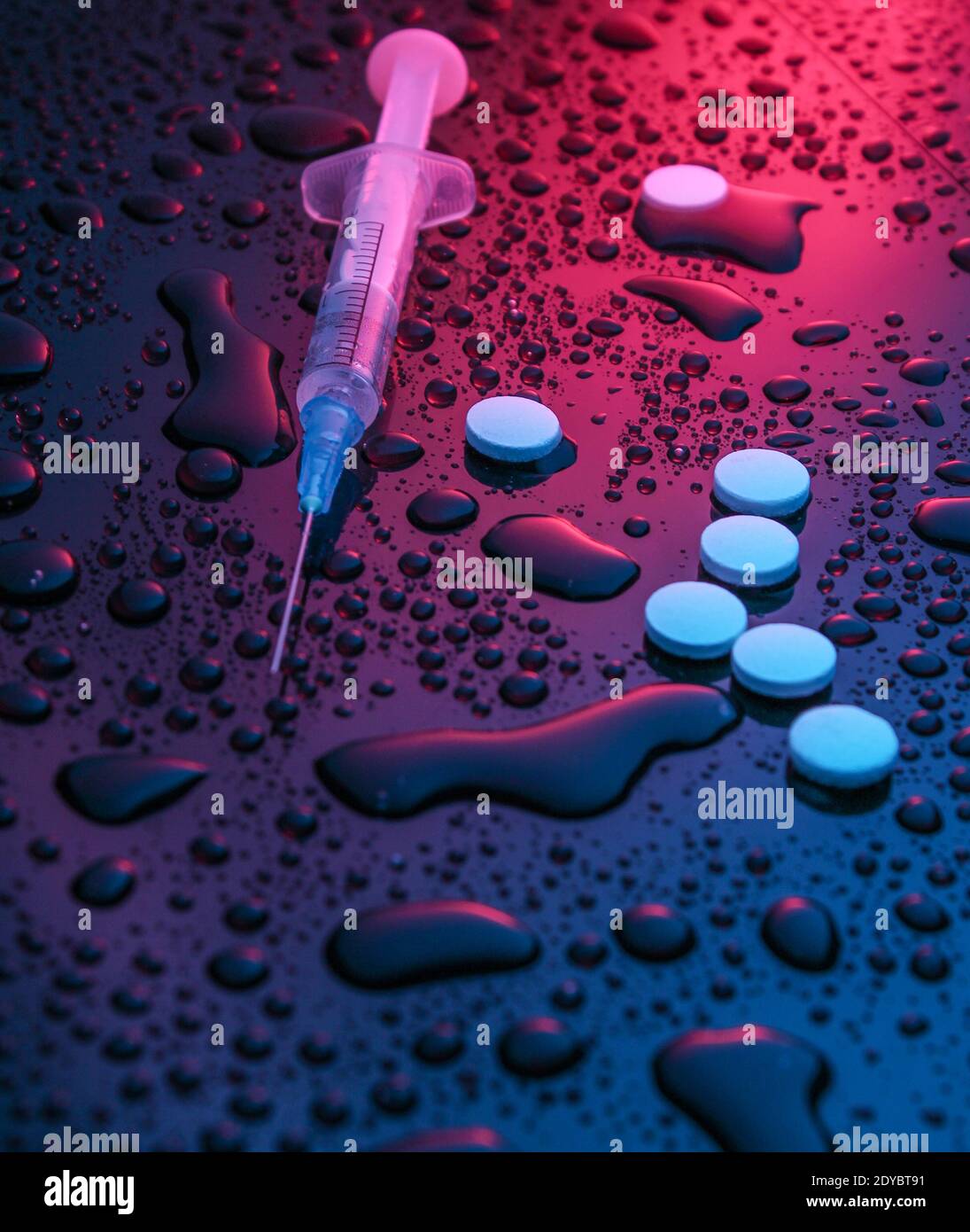 Drug concept, addiction. Syringe and pills on dark background with ...