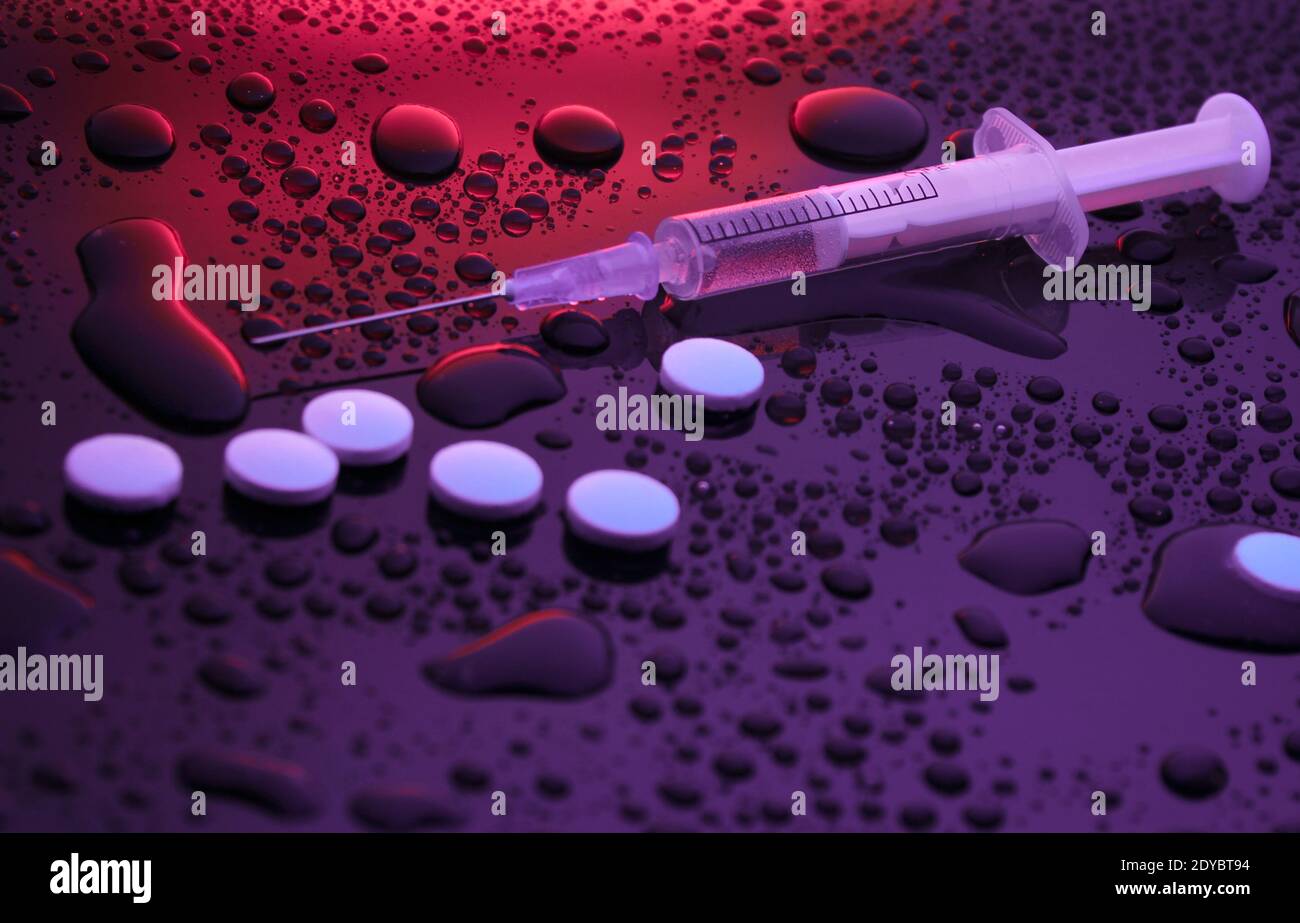 Drug concept, addiction. Syringe and pills on dark background with ...