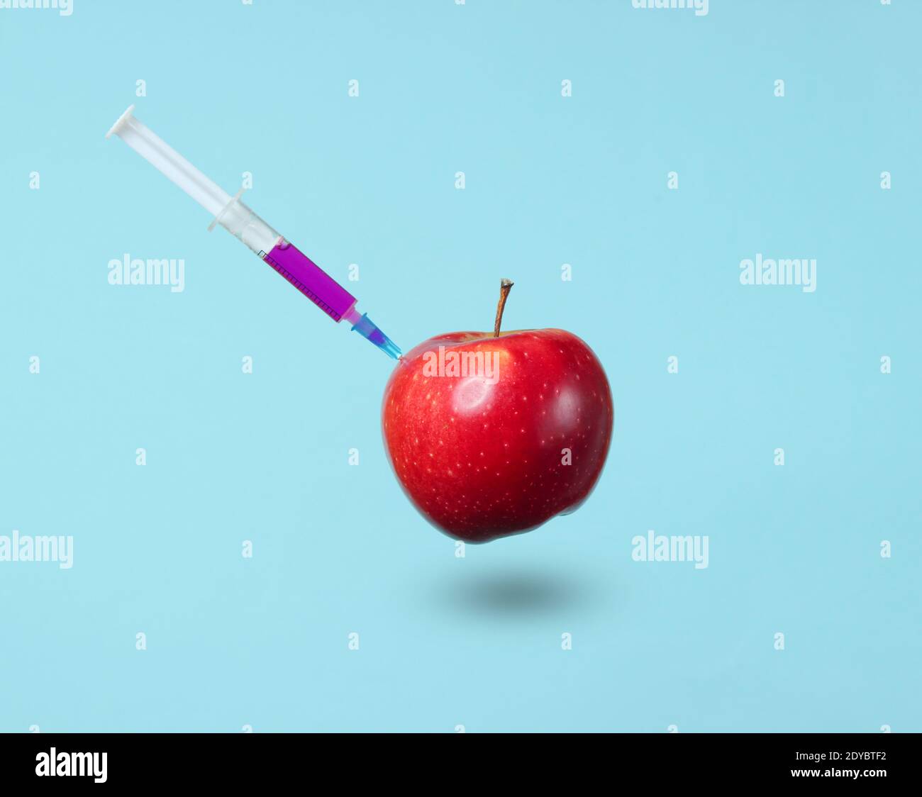 Genetically modified Red Apple with syringes on blue background ...