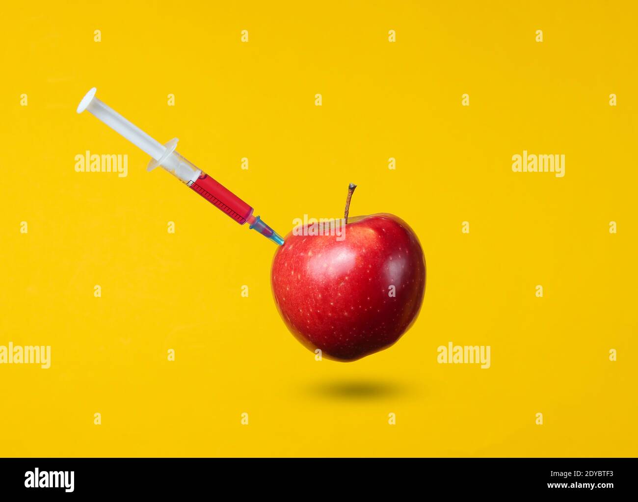 Genetically modified Red Apple with syringes on yellow background ...
