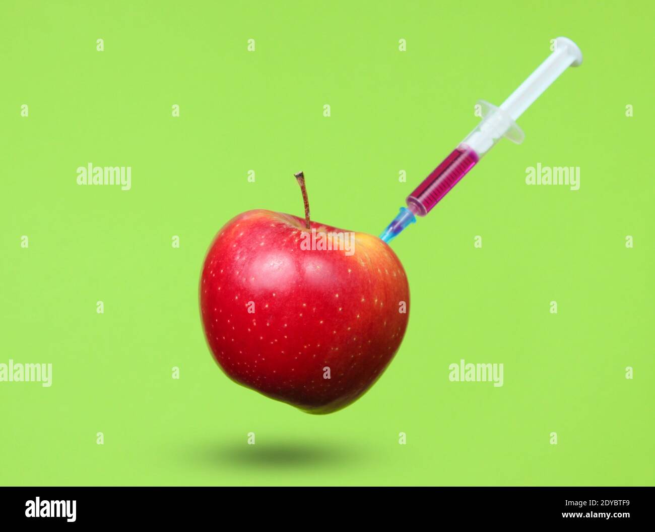 Genetically modified Red Apple with syringes on green background ...