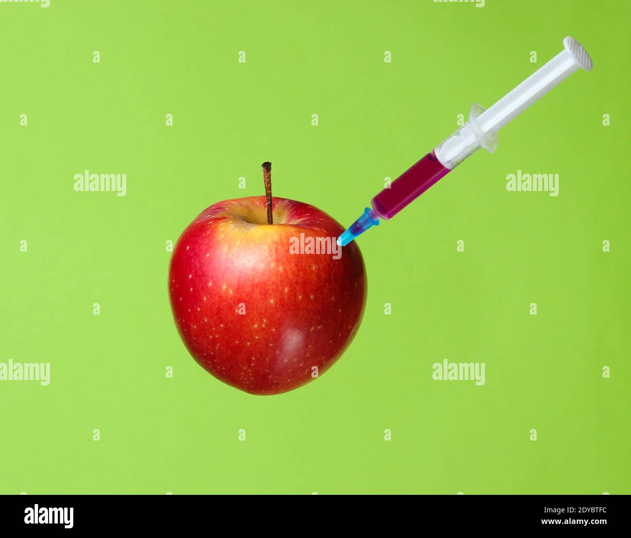 Genetically modified Red Apple with syringes on green background ...