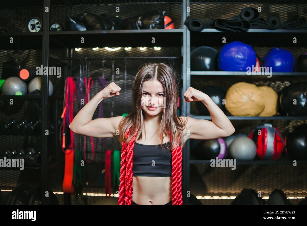Muscular young woman in sportswear with a rope around her neck posing ...