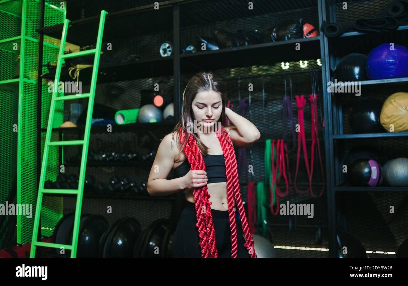 Muscular young woman in sportswear with a rope around her neck posing ...