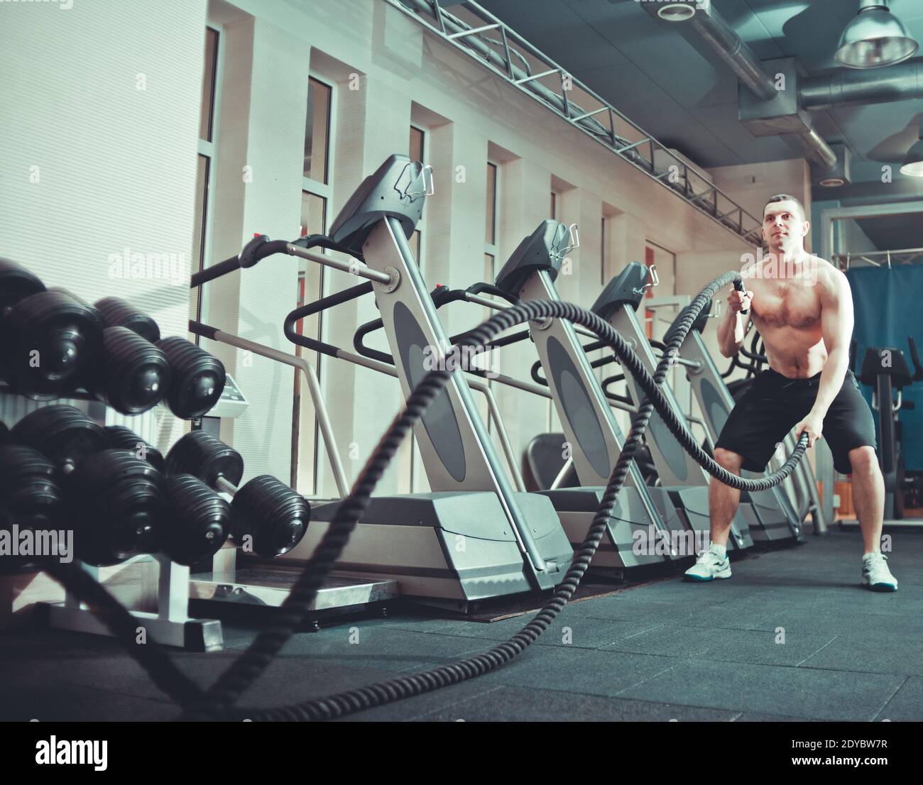 Workout concept. Powerful attractive young man workout with ropes at ...