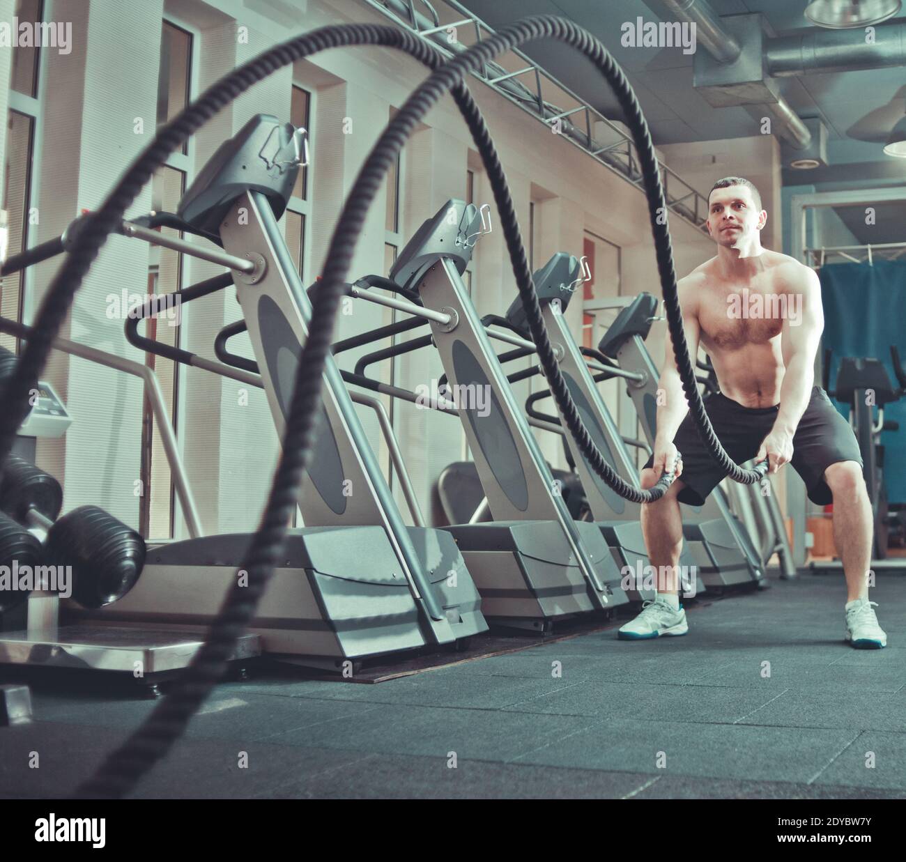 Workout concept. Powerful attractive young man workout with ropes at ...