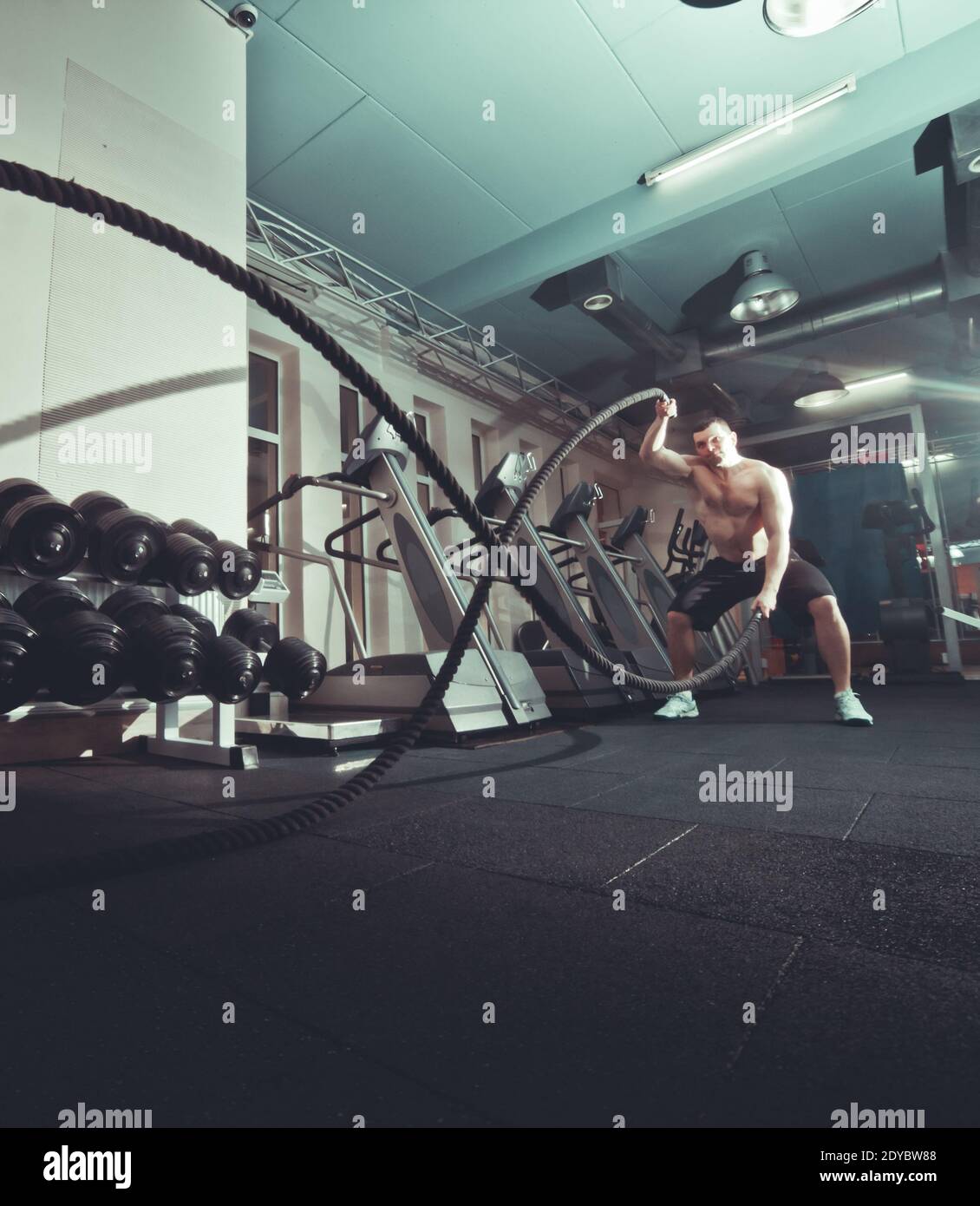 Workout concept. Powerful attractive young man workout with ropes at ...