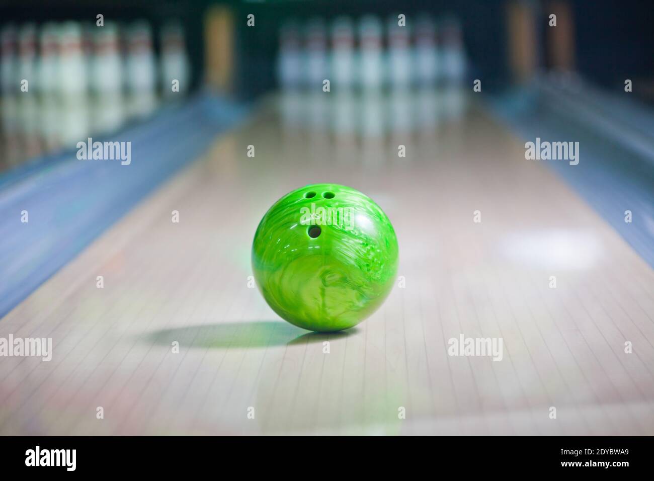 Green Bowling ball put on alley with blurred bowling pin background ...