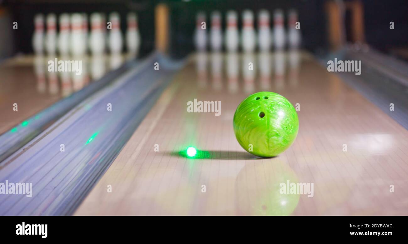 Green Bowling ball put on alley with blurred bowling pin background ...