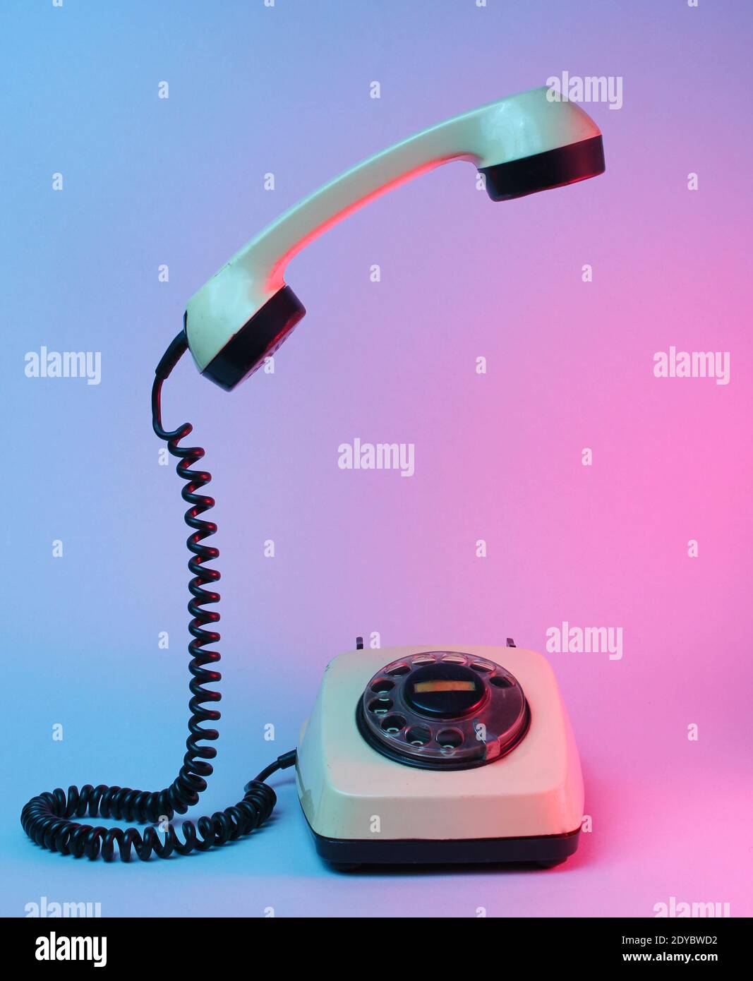 Old style rotary telephone with soaring telephone handle, blue red neon ...