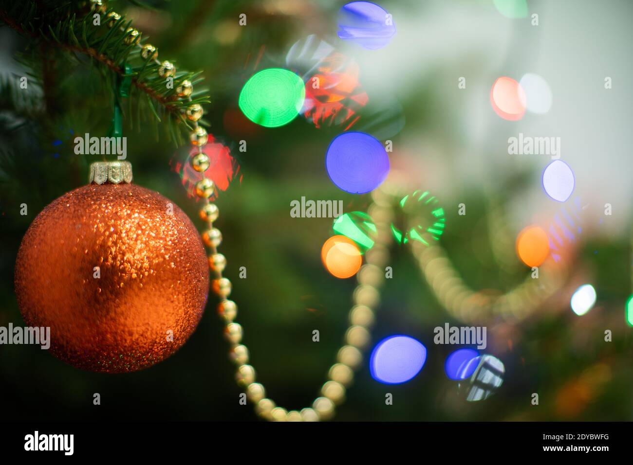 A shiny ornament in the shape of a round Christmas ball attached to a ...