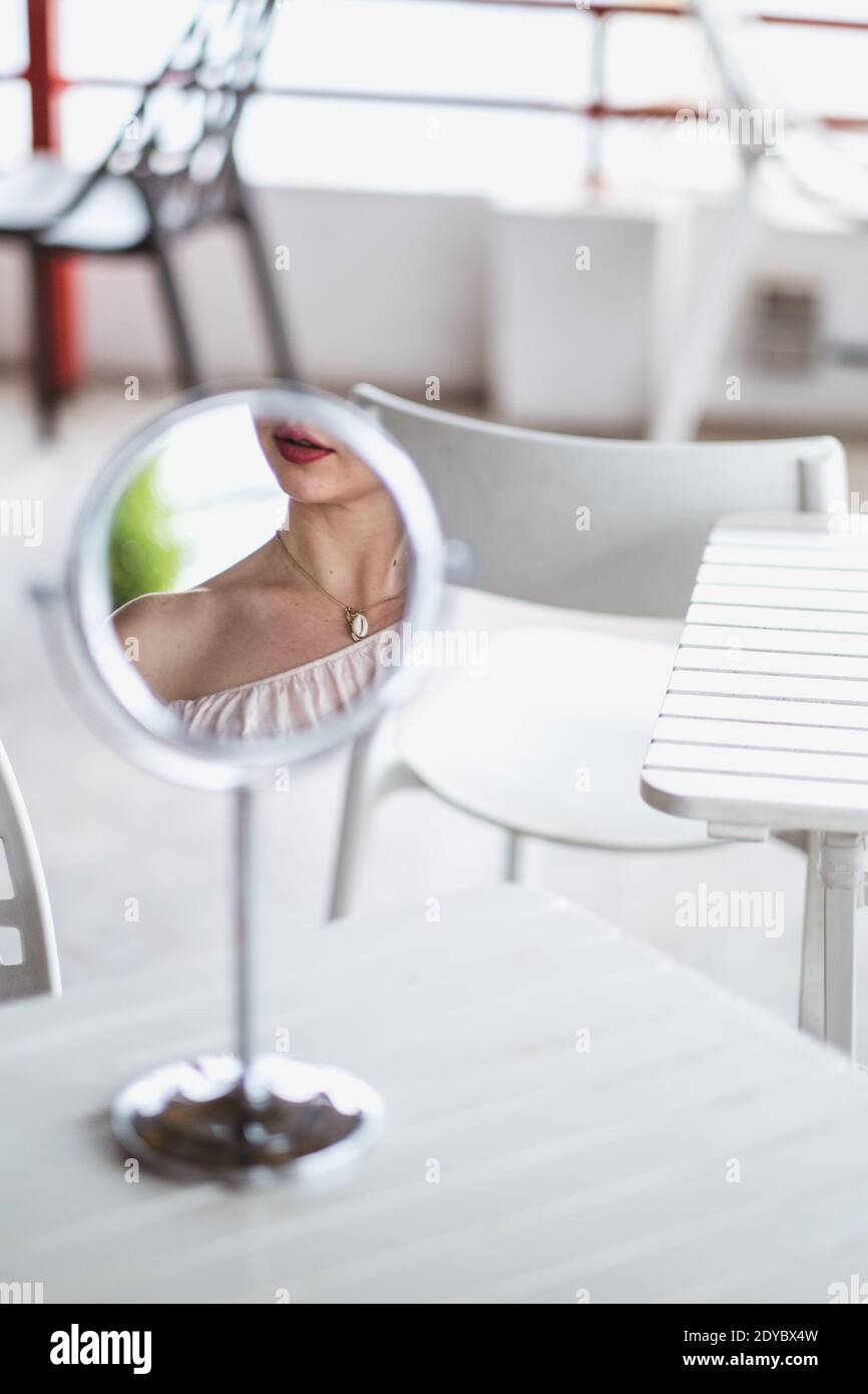 Reflection of a girls neck with a small necklace in a round mirror ...