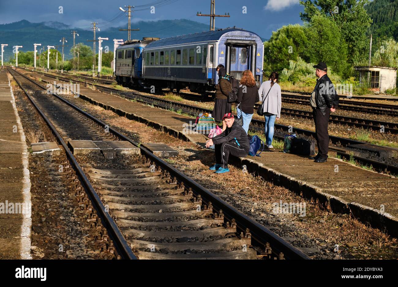 Multiple trains track of desolate station in Romania with dark gloomy clouds in horizon. People ...