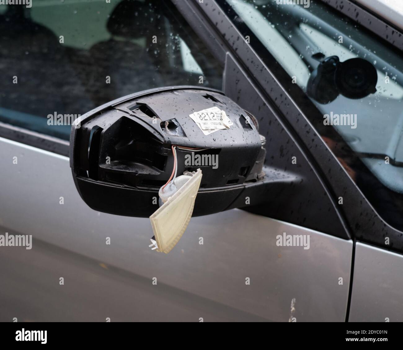 Broken side view mirror of car, still attached with parts hanging on ...