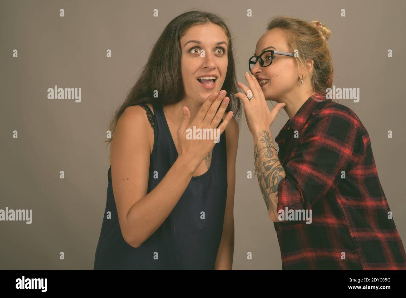 Two young beautiful woman friends against gray background Stock Photo ...